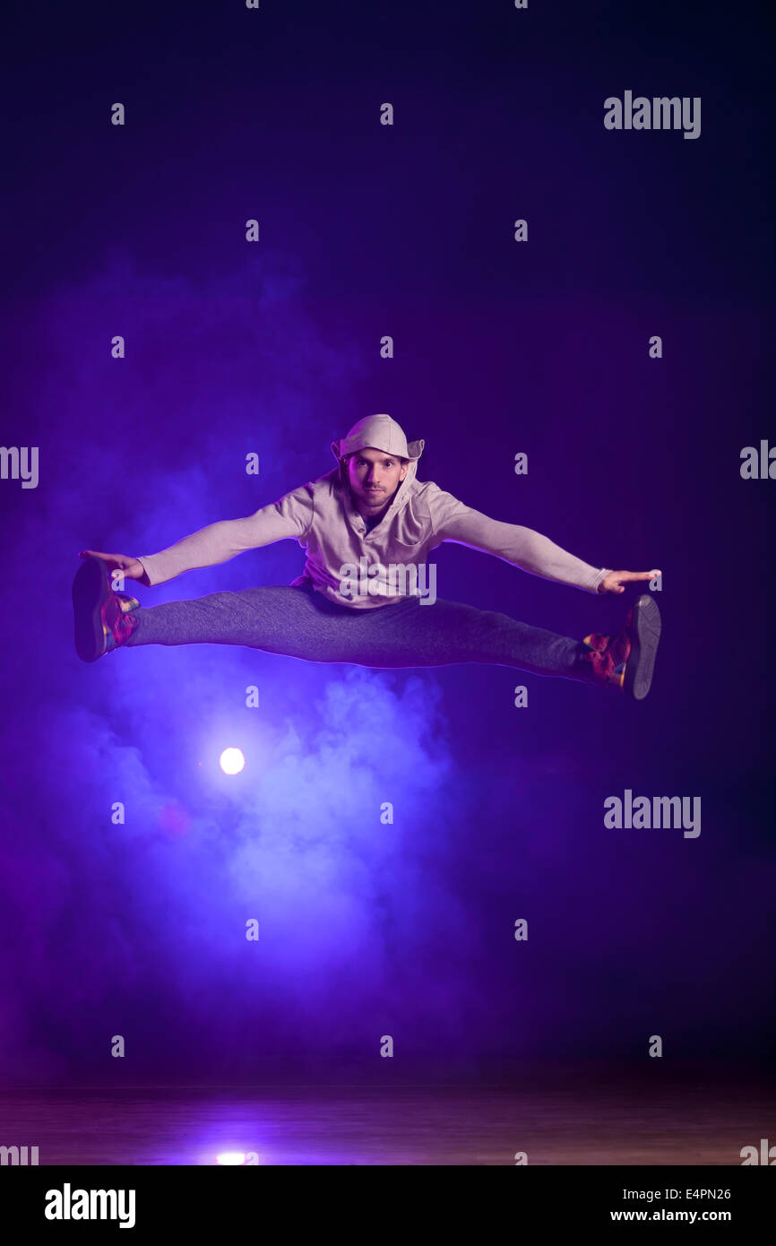 Young and muscular man performing a contemporary dance pose on a stage ...