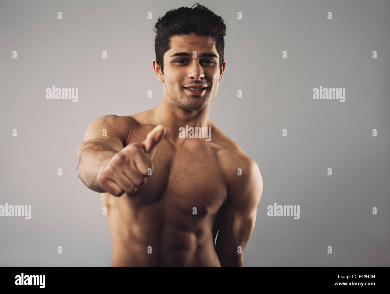 Portrait of a happy muscular young guy gesturing thumbs up sign ...