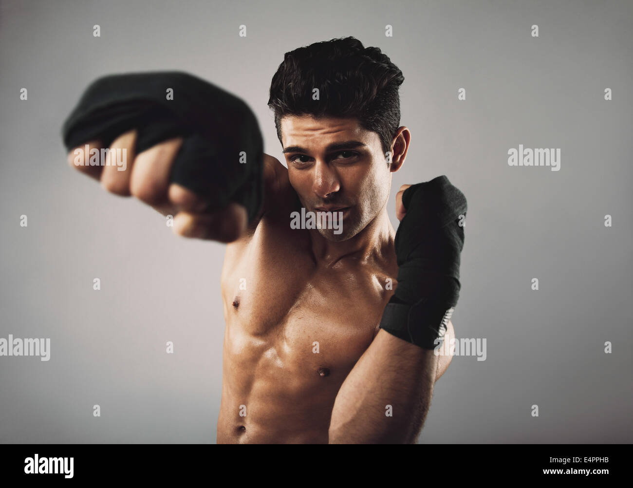 Portrait of strong young man wearing boxing gloves practicing shadow ...