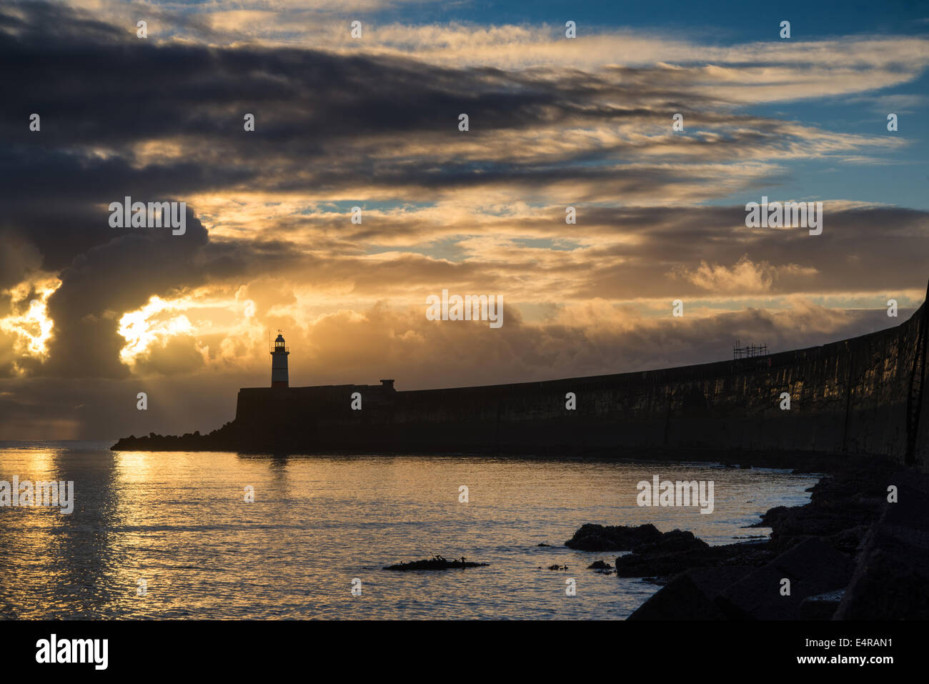 Stunning sunrise over ocean with lighthouse and harbor wall Stock Photo ...