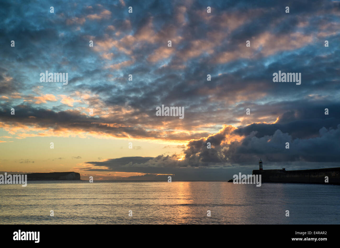 Stunning sunrise over ocean with lighthouse and harbor wall Stock Photo ...