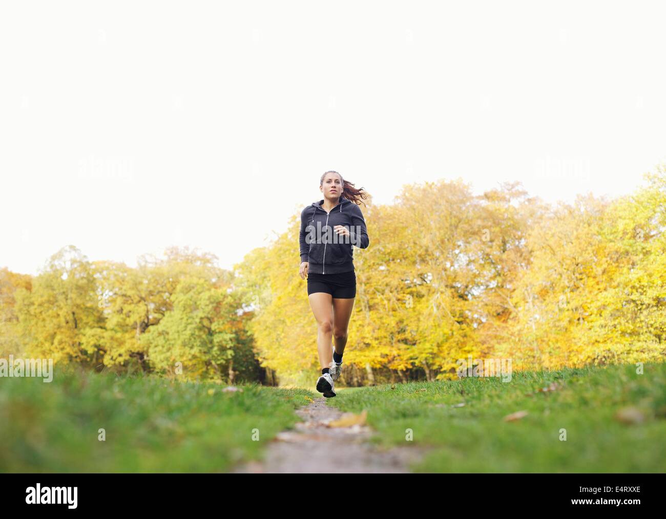 Fit and healthy young woman running outside in park. Fitness model in ...