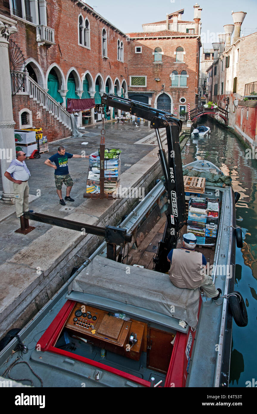 Men using crane to load fresh vegetables and fruit onto barge at Rialto ...