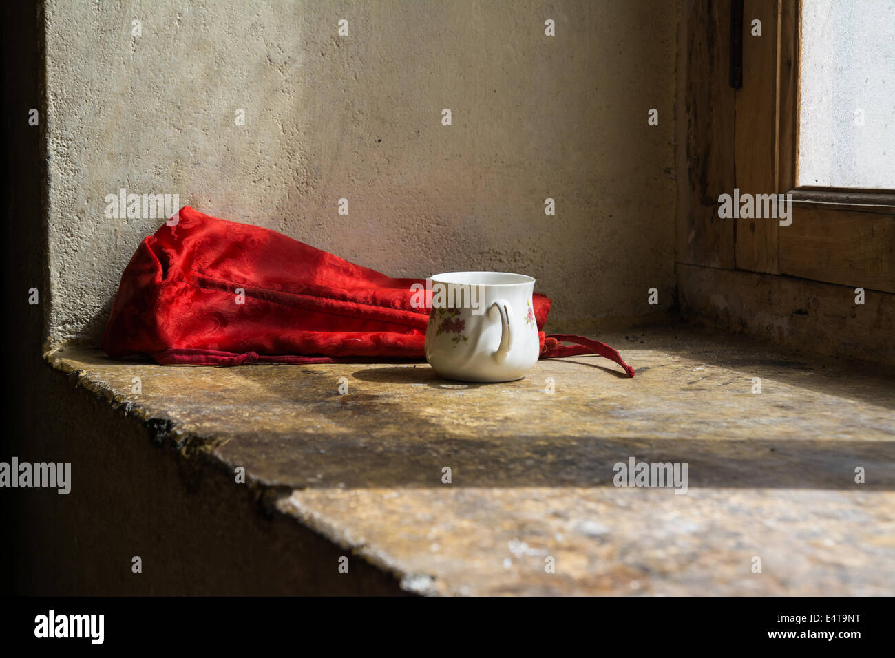 Still life. Discarded red bag and empty cup on window sill in a room ...
