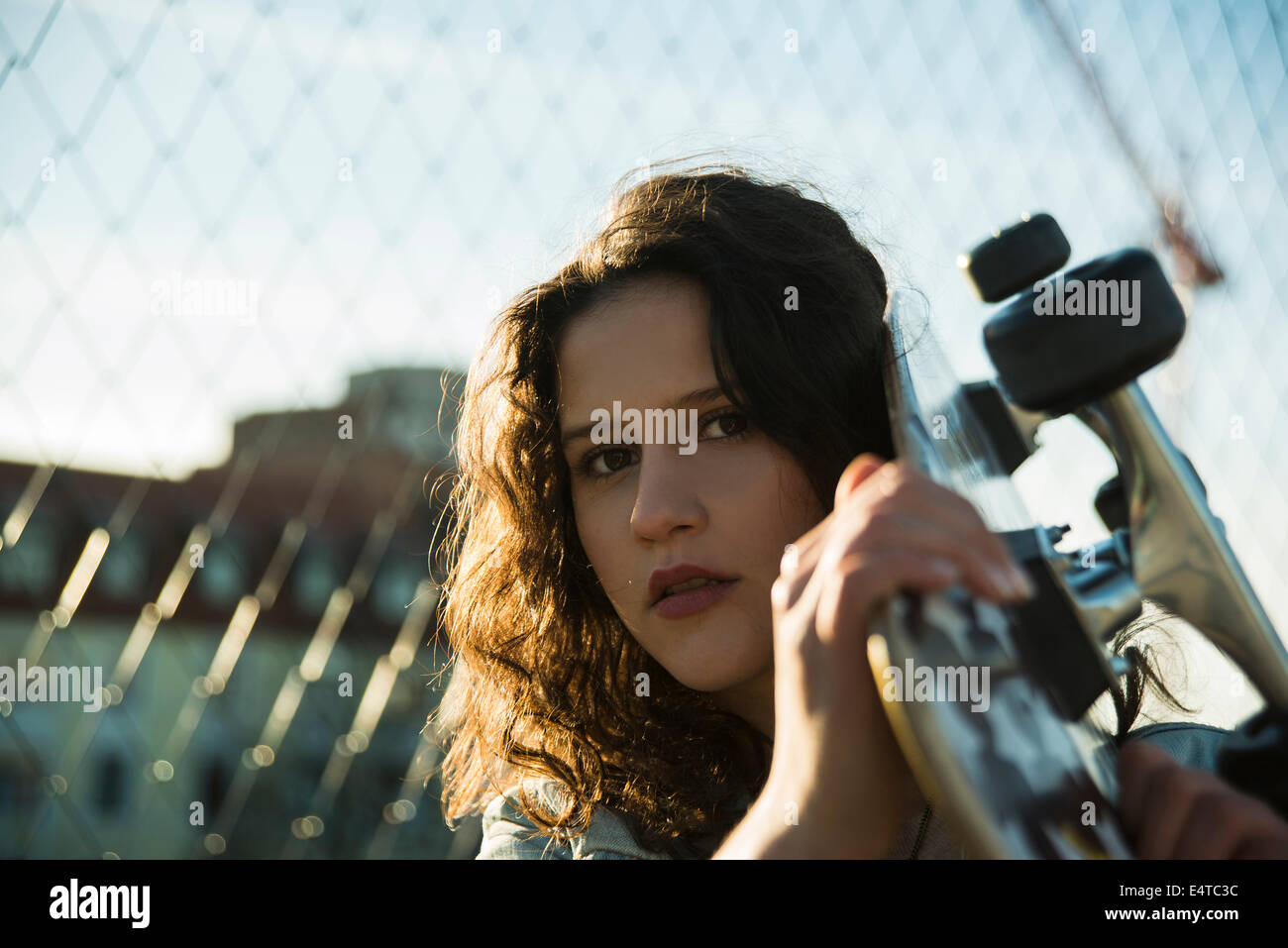 Close-up portrait of teenage girl standing outdoors next to chain link ...