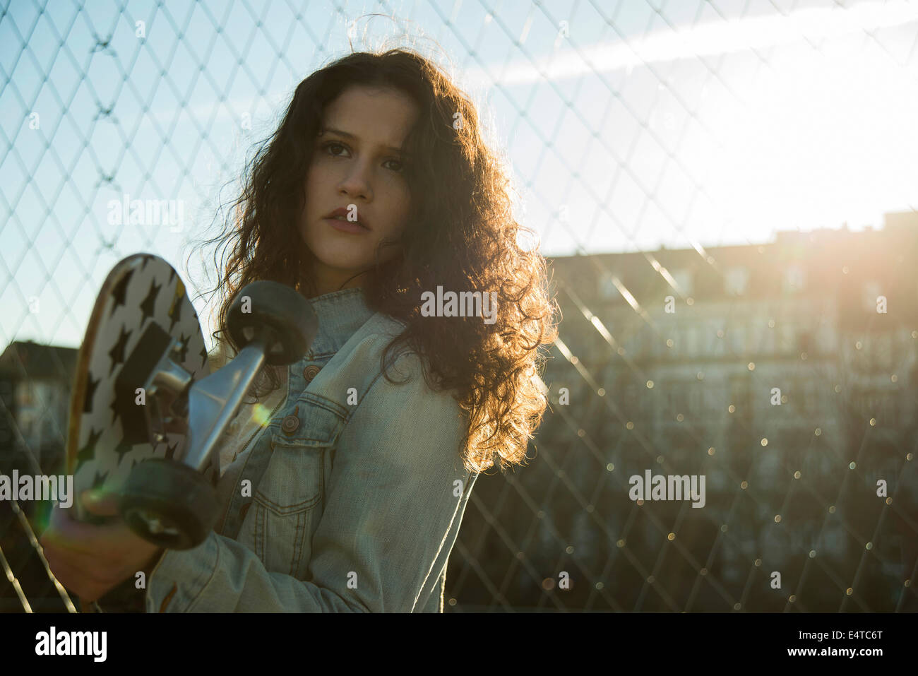 Portrait of teenage girl standing outdoors next to chain link fence ...