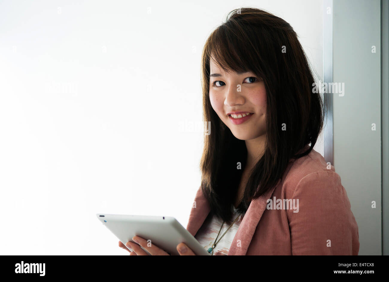Close-up portrait of young woman holding tablet computer, looking at ...