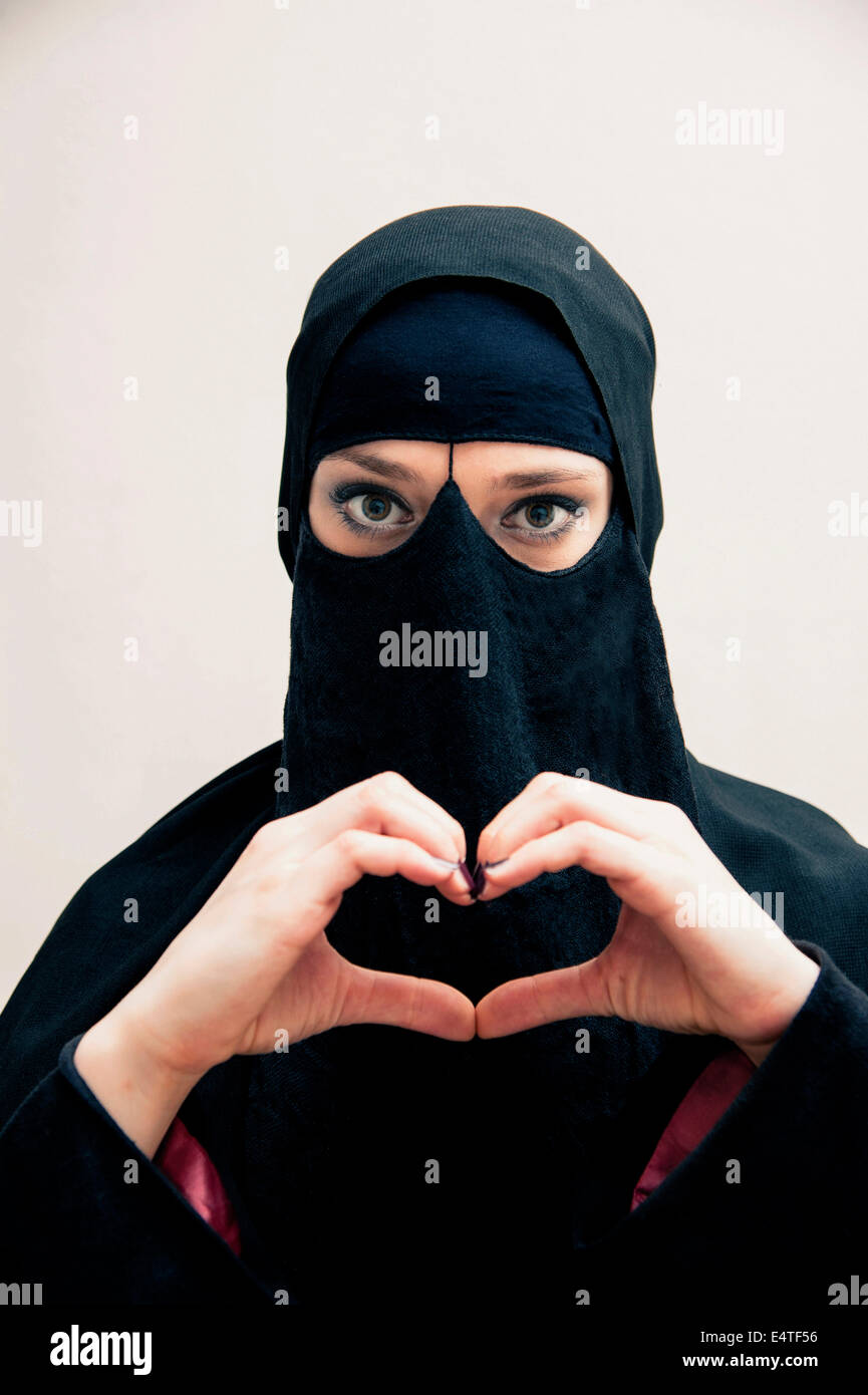 Portrait of young woman in black, muslim hijab and muslim dress, making ...