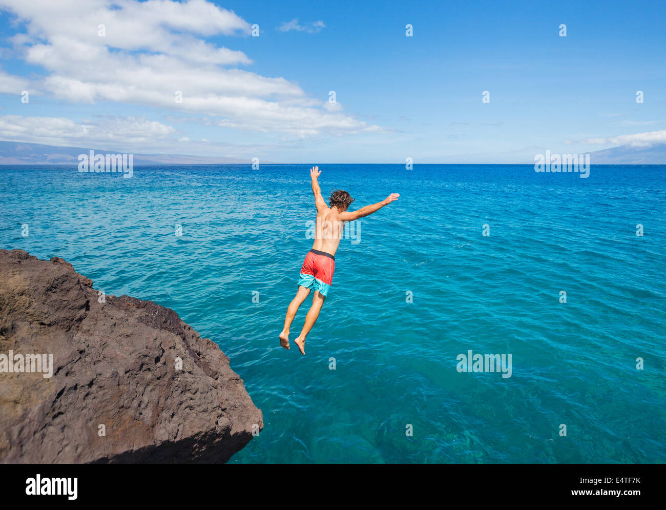 Man jumping off cliff into the ocean. Summer fun lifestyle Stock Photo ...