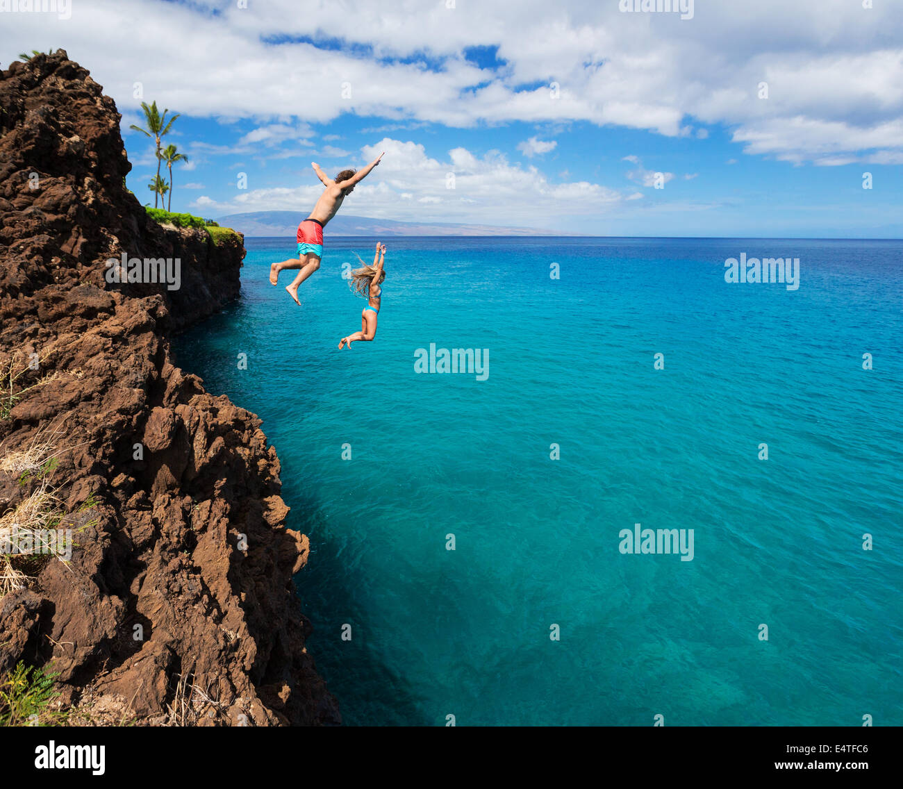 Summer fun, Friends cliff jumping into the ocean Stock Photo - Alamy
