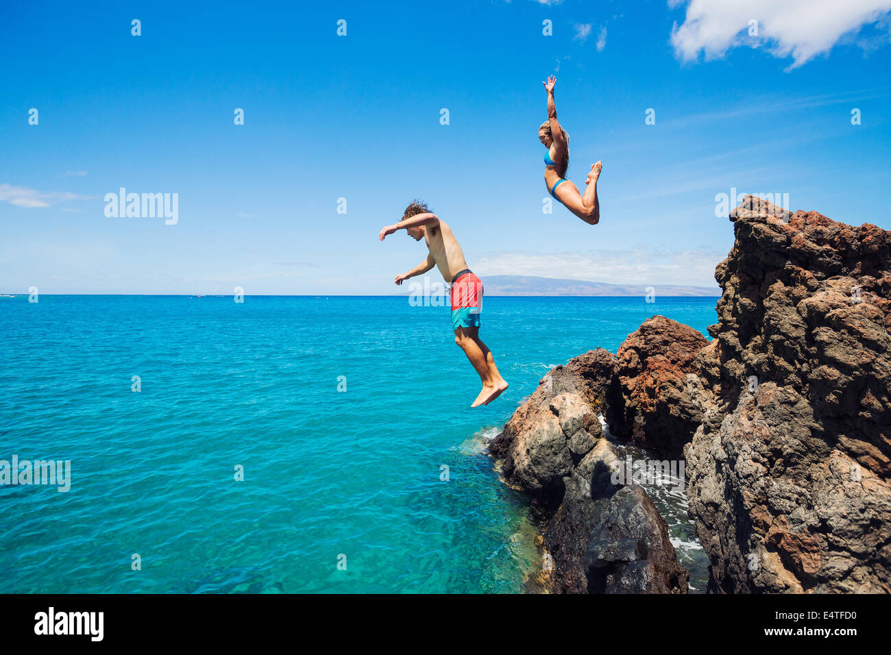 Summer fun, Friends cliff jumping into the ocean Stock Photo - Alamy