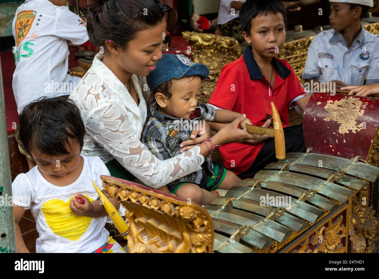Bali, Indonesia. Balinese Hindu Mother Showing Child how to Hit a ...
