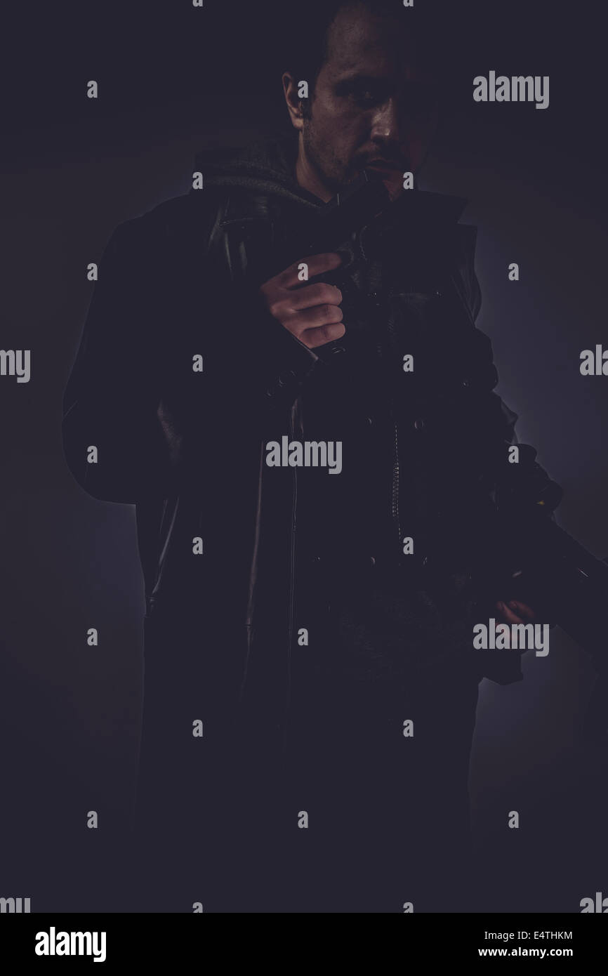 dark portrait of stylish man with long leather jacket, gun armed Stock ...