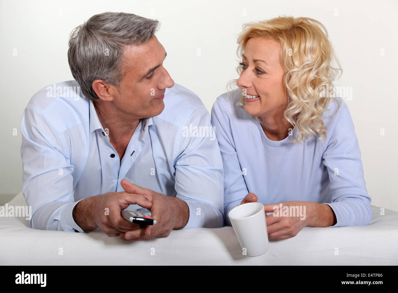 Couple laying on bed watching television Stock Photo - Alamy