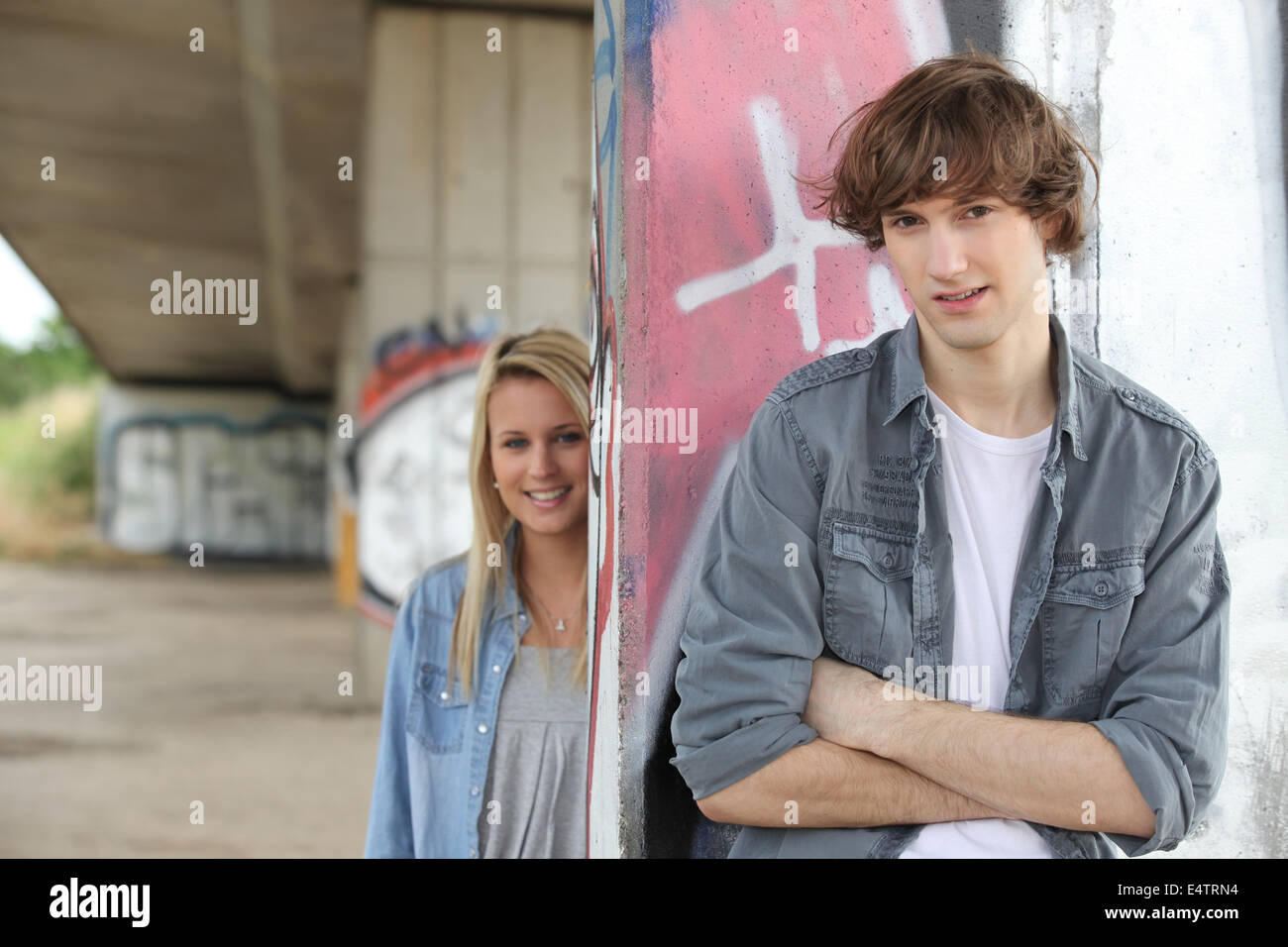 Urban couple stood by gratified wall Stock Photo - Alamy