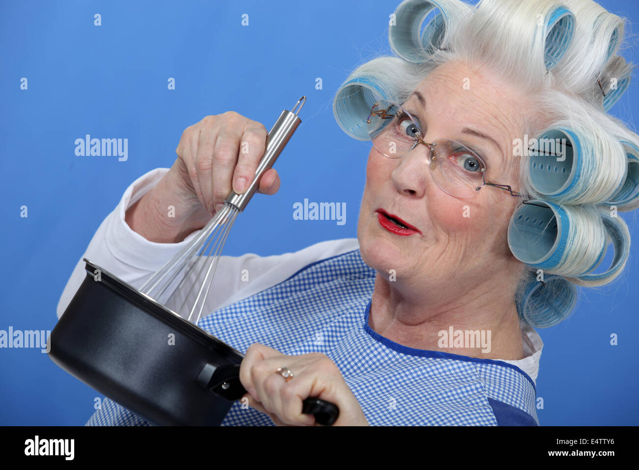 Cheeky older woman in rollers whisking sauce Stock Photo - Alamy
