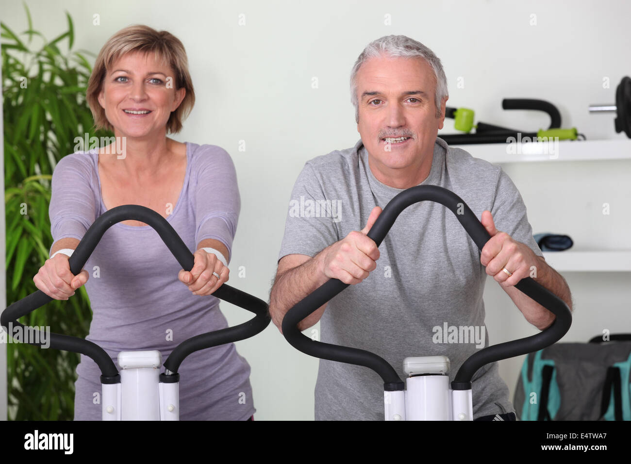 Couple riding exercise bikes Stock Photo - Alamy