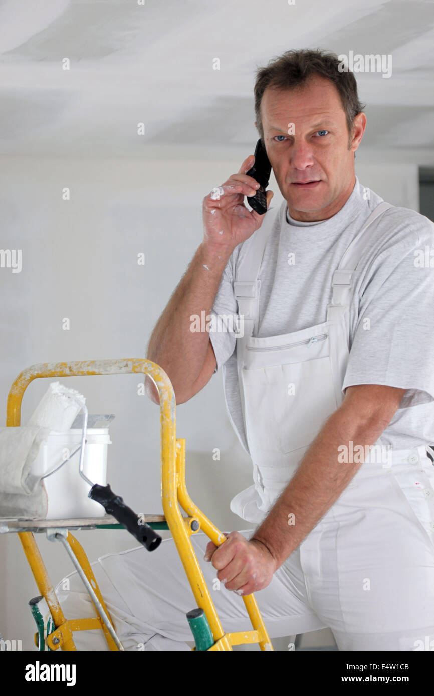 Painter answering phone whilst working Stock Photo - Alamy