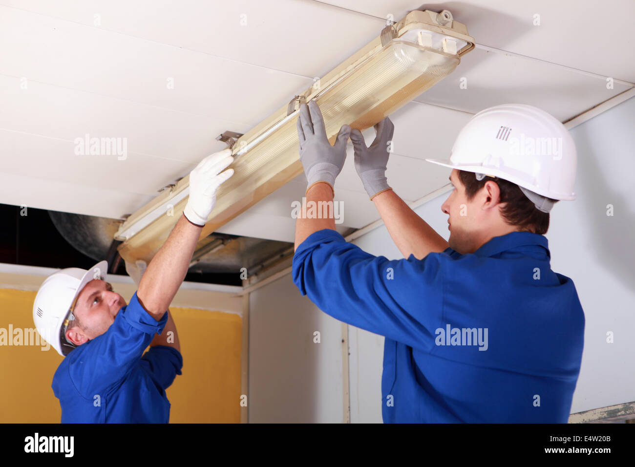 Two electrician repairing office lighting Stock Photo - Alamy