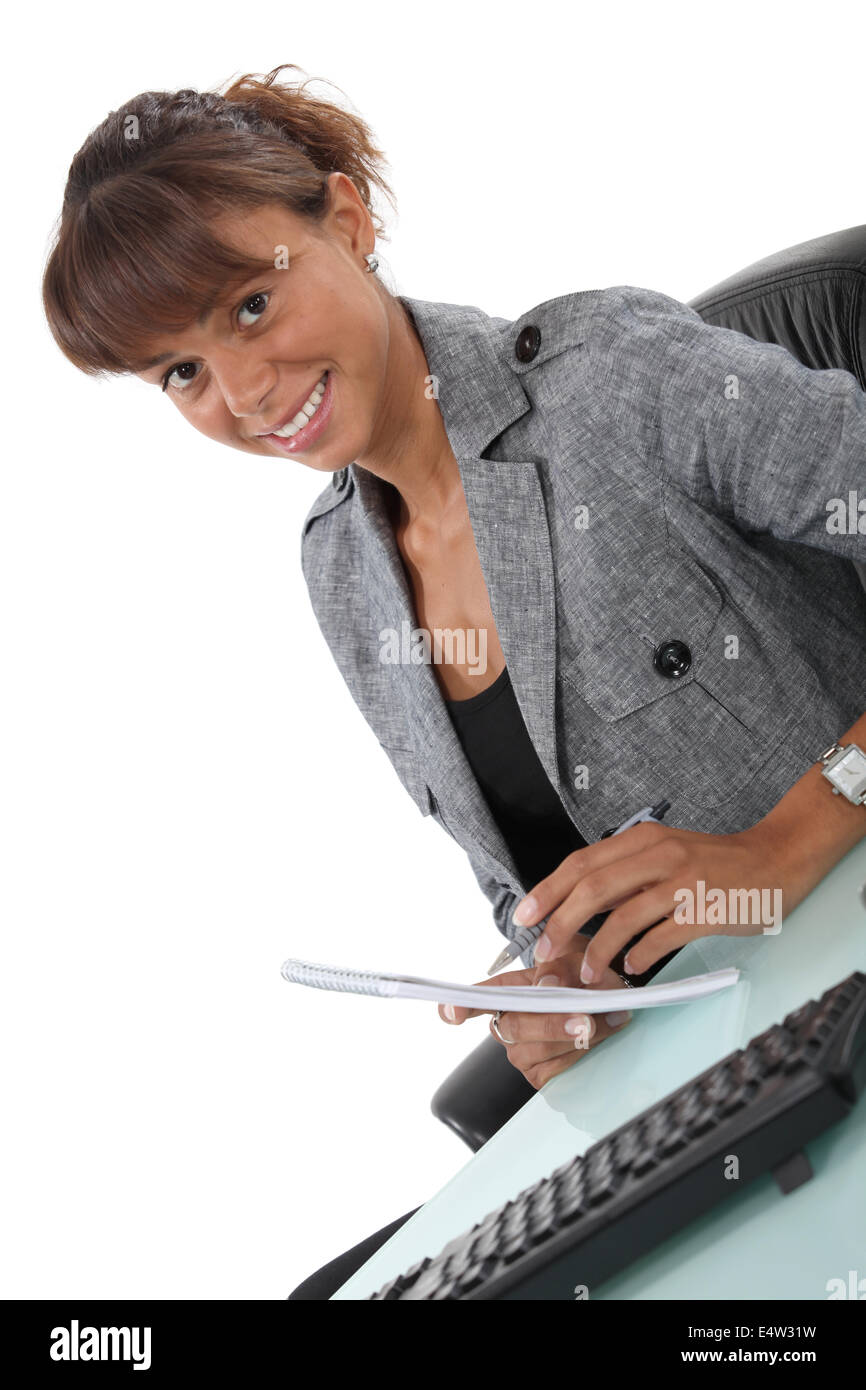 Happy office worker writing at her desk Stock Photo - Alamy