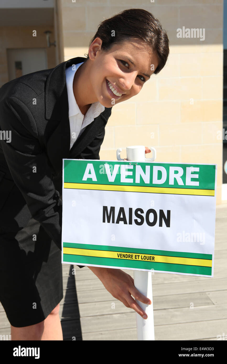 Woman putting home for sale sign Stock Photo - Alamy