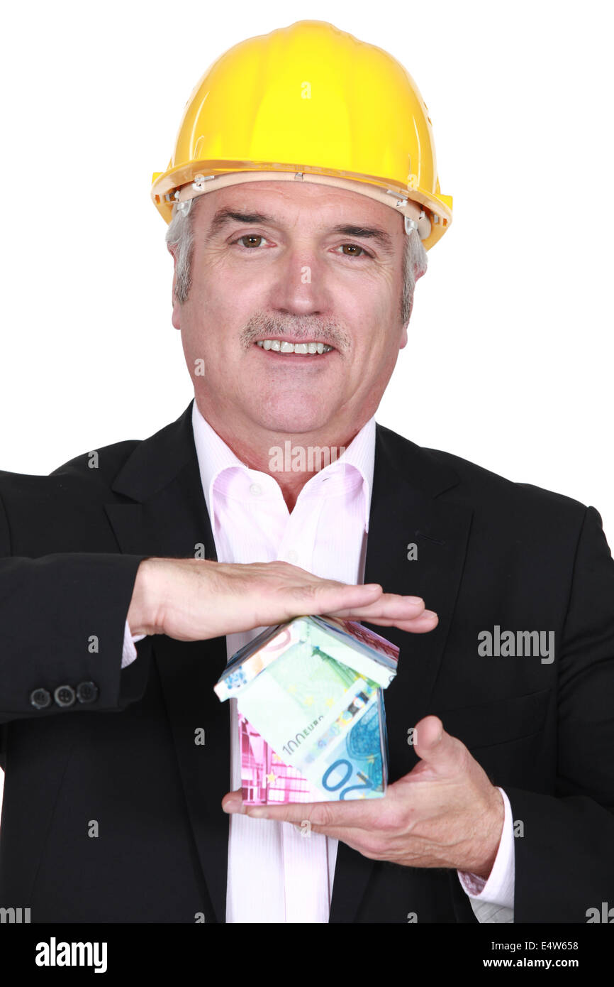 Architect holding house made of money Stock Photo - Alamy