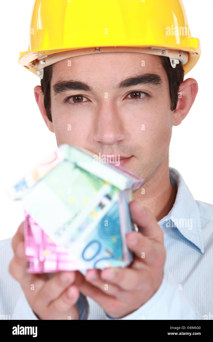 Builder with a house made of money Stock Photo - Alamy