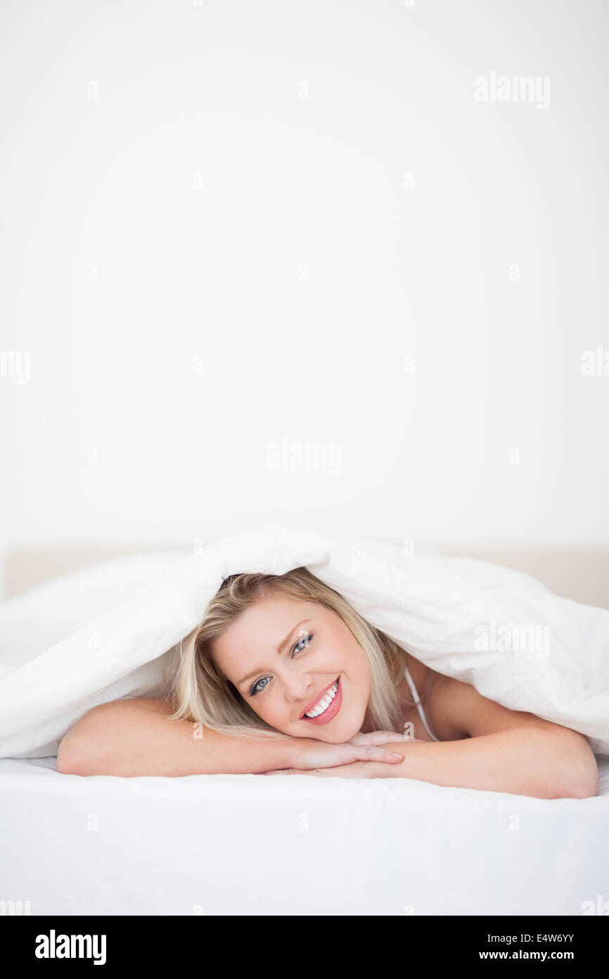Blonde woman lying under a duvet Stock Photo - Alamy