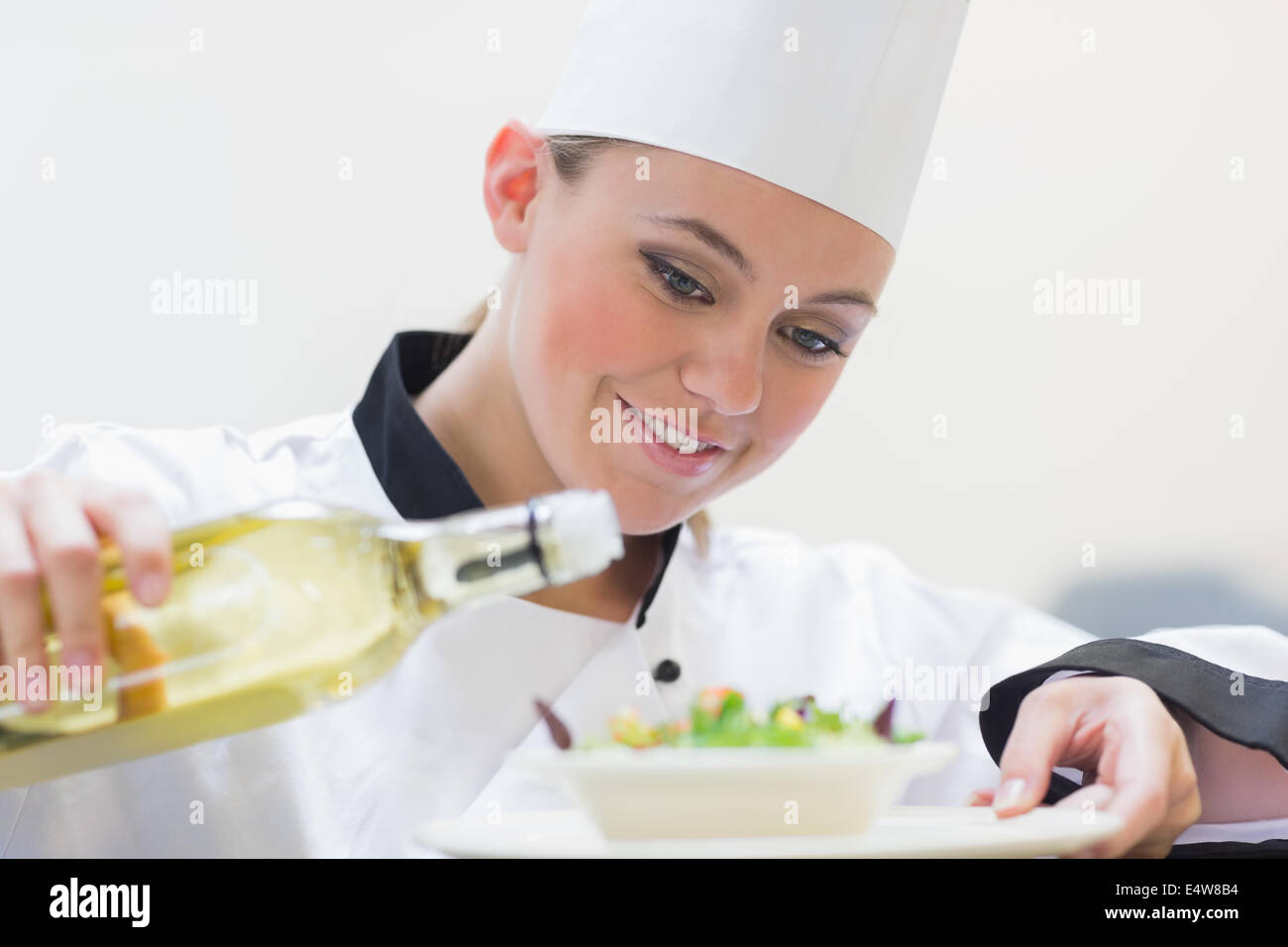 Chef pouring oil over salad Stock Photo - Alamy