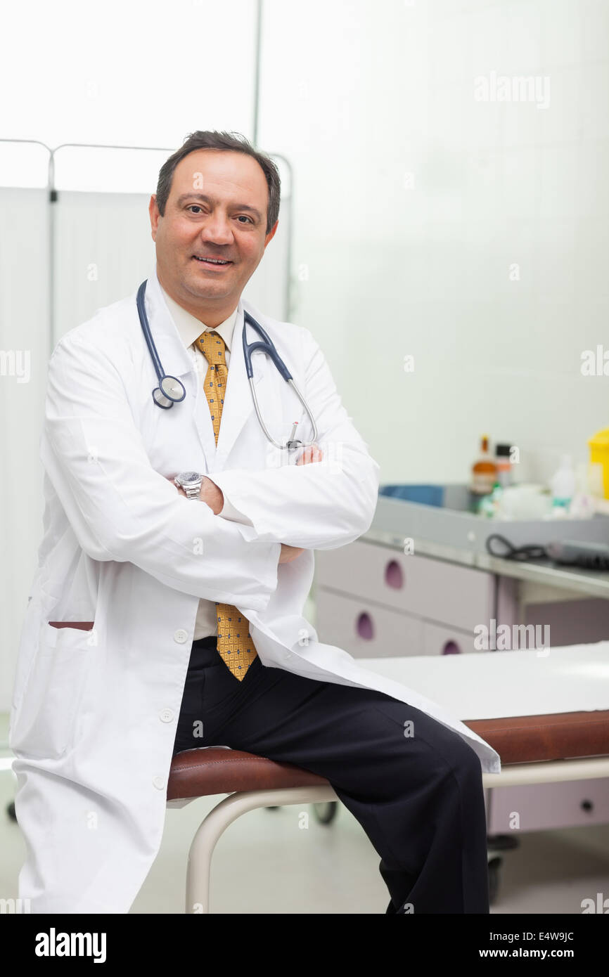 Doctor smiling while sitting on a table Stock Photo - Alamy
