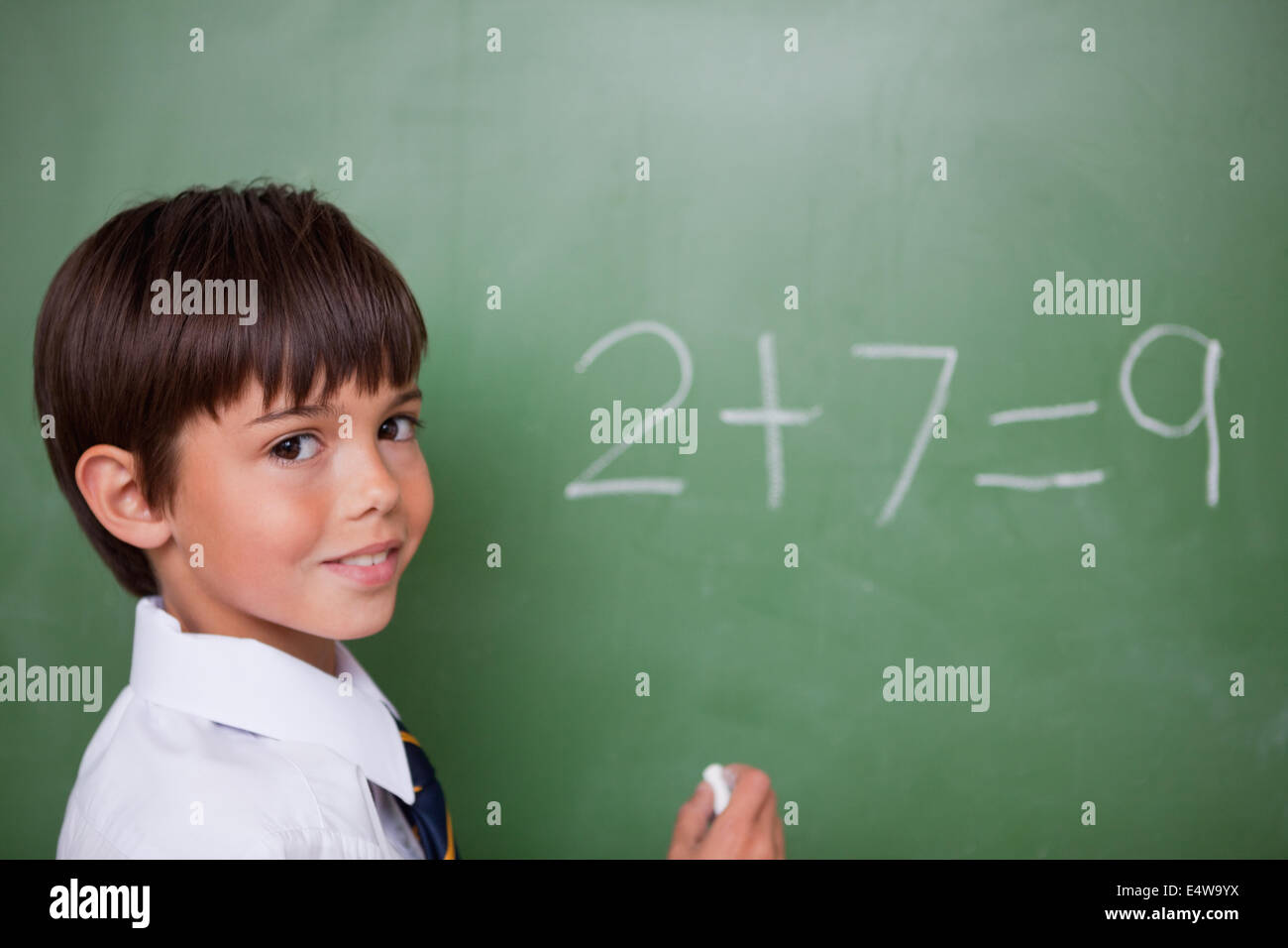 Smiling schoolboy writing an addition Stock Photo - Alamy