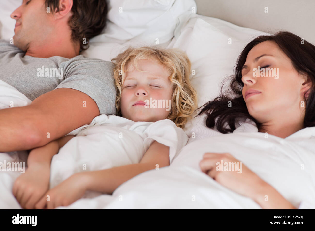 Boy sleeping between his parents Stock Photo - Alamy