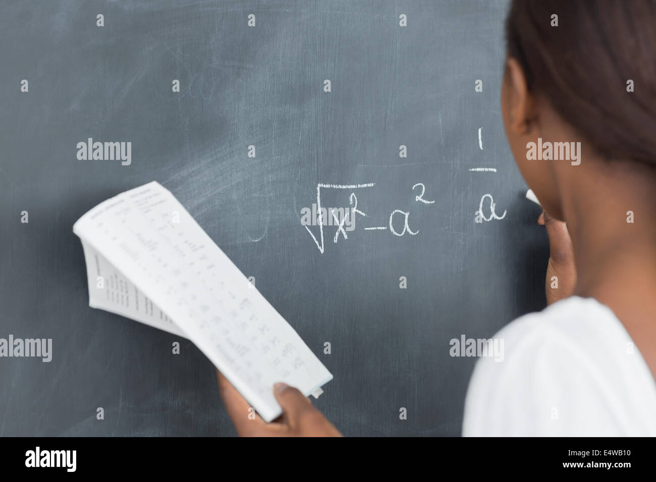 Student writing on a blackboard Stock Photo - Alamy