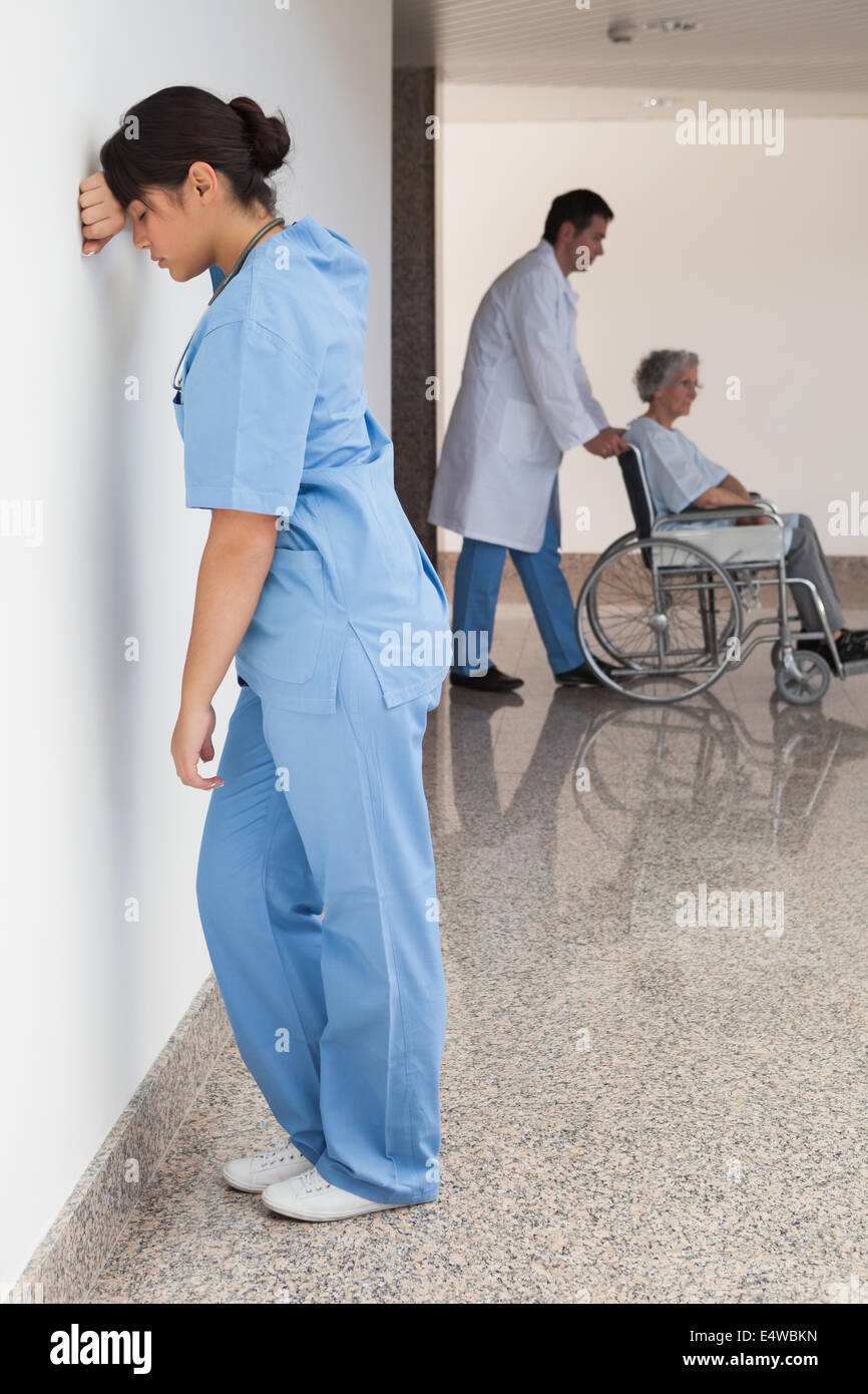 Distressed nurse standing against wall Stock Photo - Alamy
