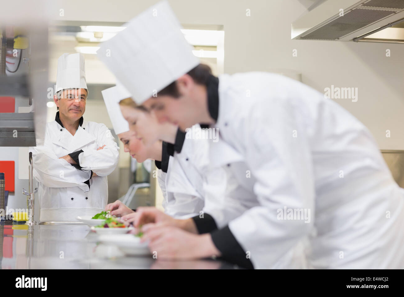 Chef overlooking others preparing salads Stock Photo - Alamy