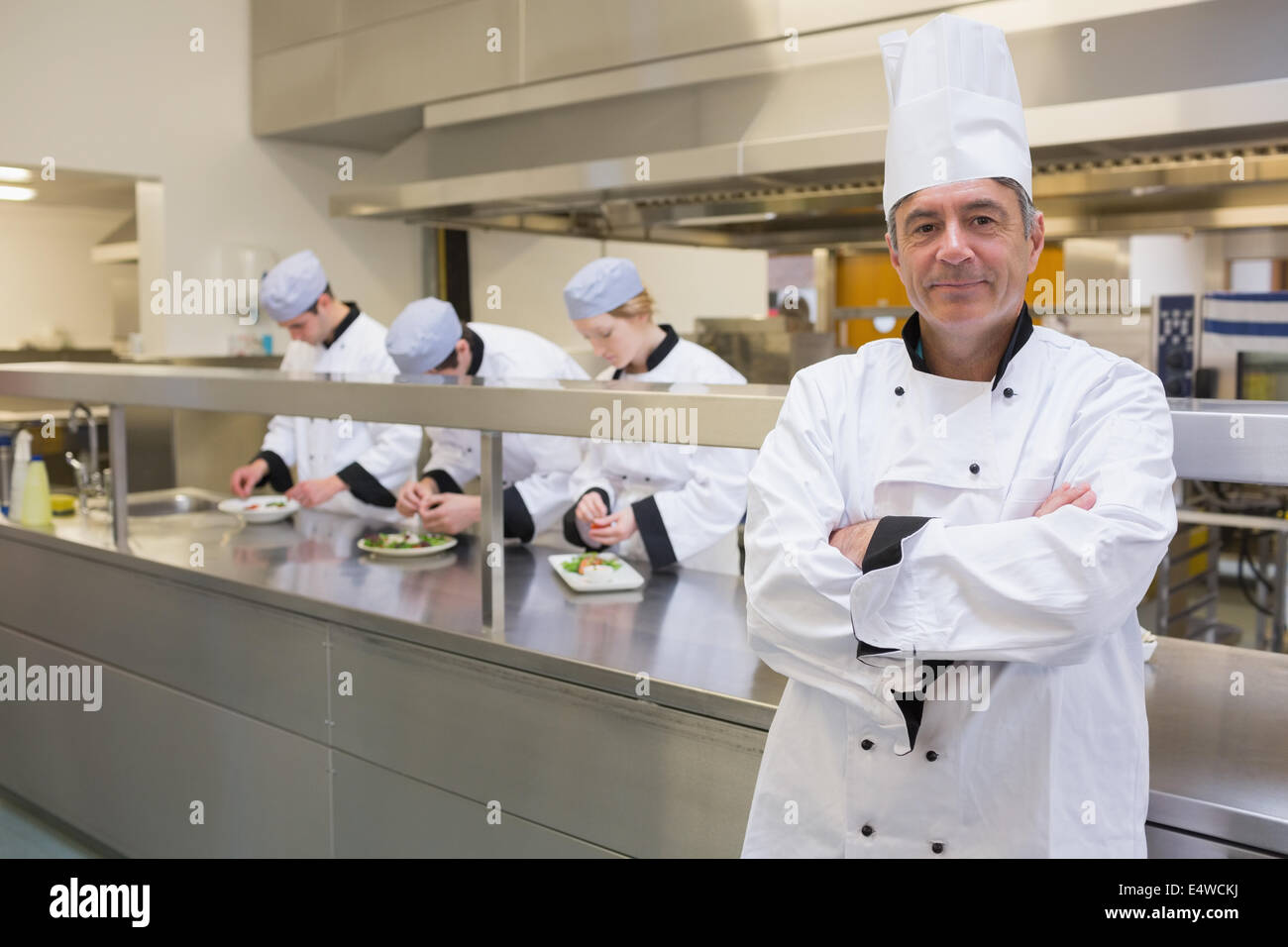 Head chef smiling in busy kitchen Stock Photo - Alamy