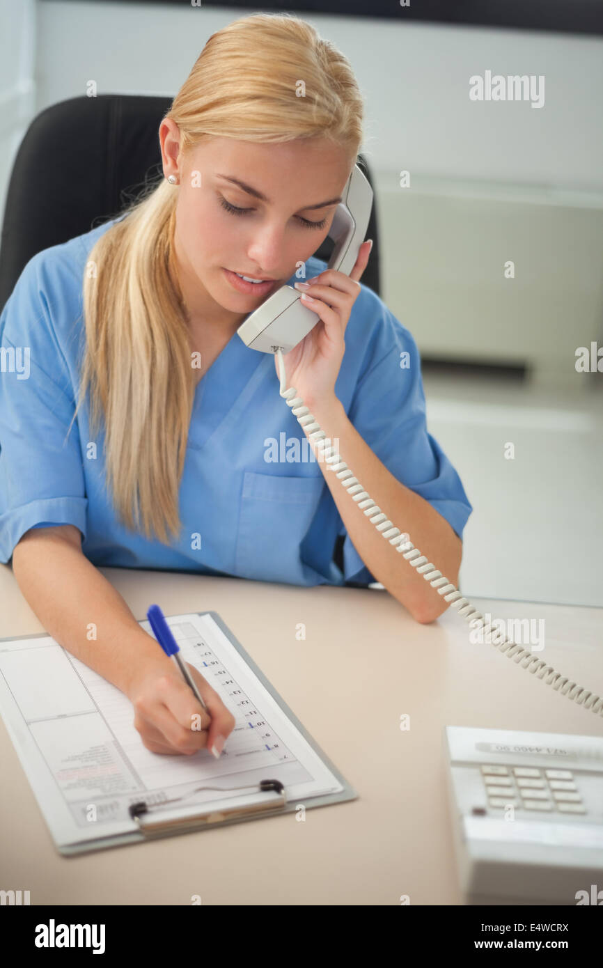 Nurse calling while writing on a clipboard Stock Photo - Alamy