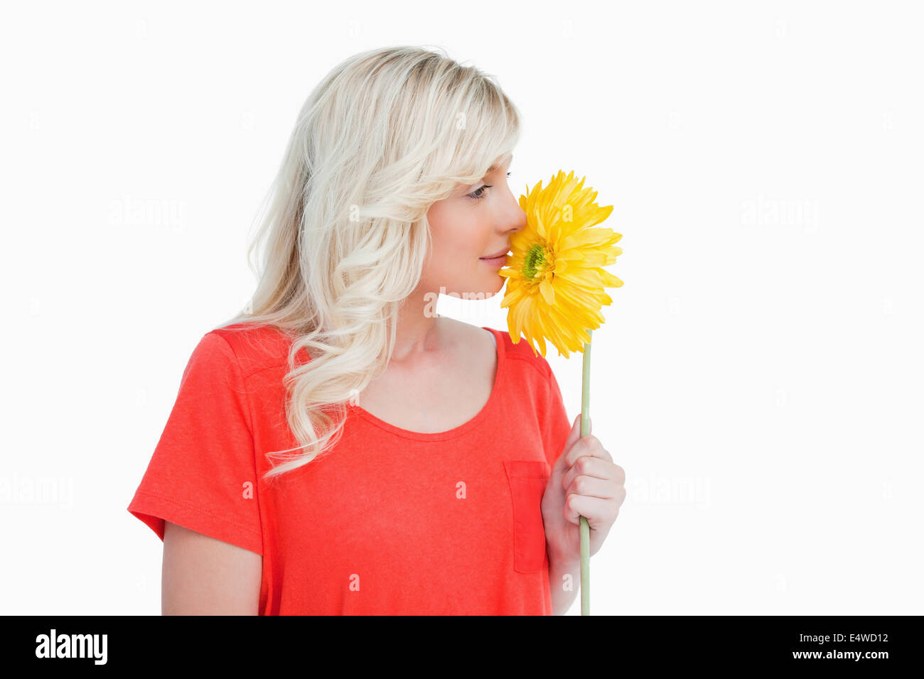 Young blonde woman smelling a yellow flower Stock Photo - Alamy