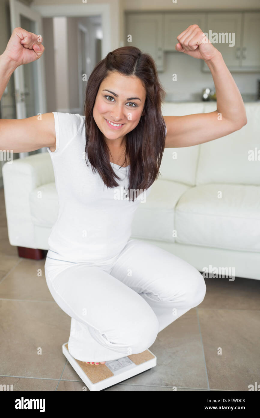 Woman celebrating on weighing scales Stock Photo - Alamy