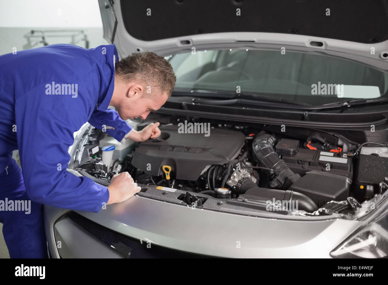 Mechanic looking at an engine of car Stock Photo - Alamy