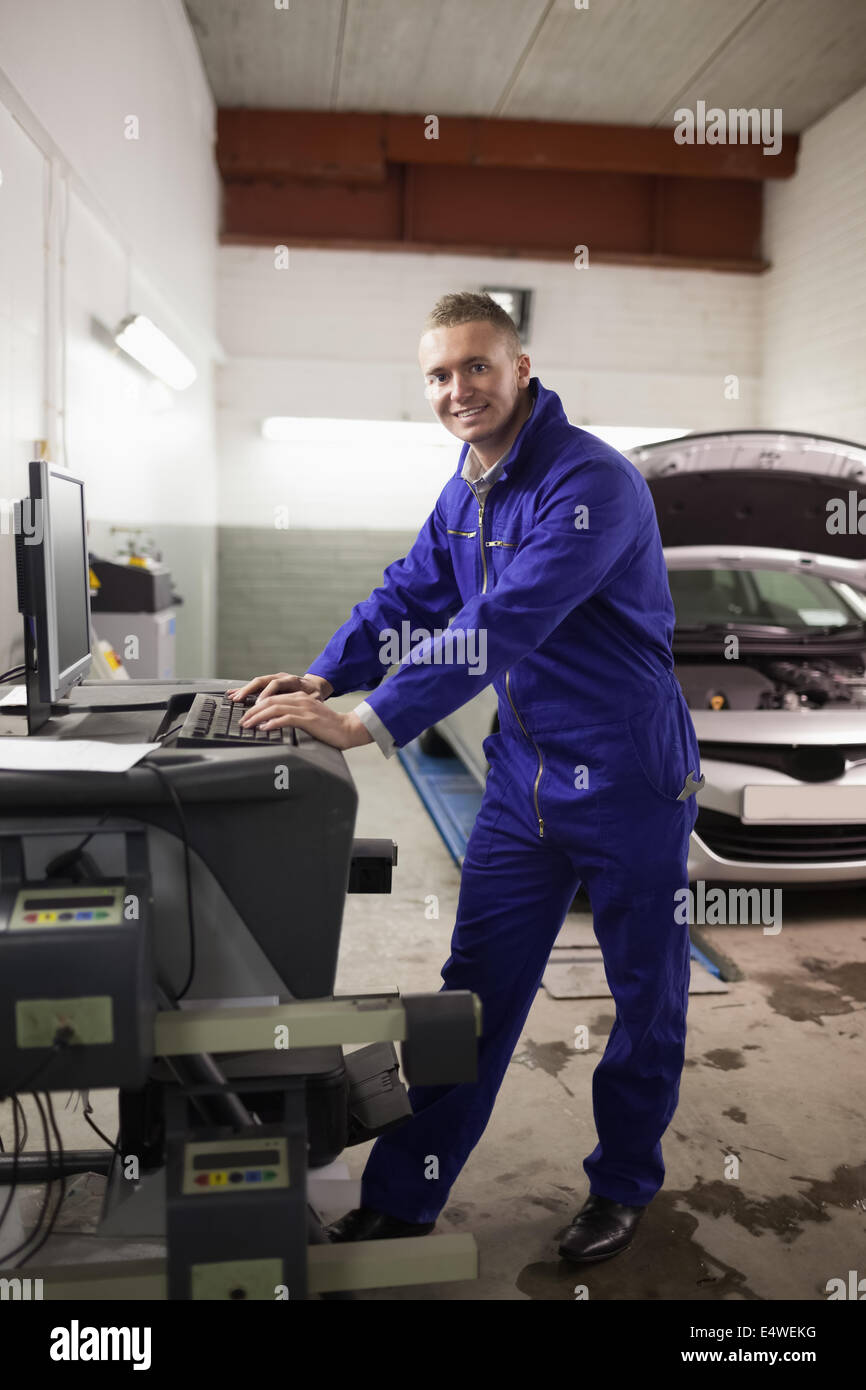 Mechanic using a computer while smiling Stock Photo - Alamy