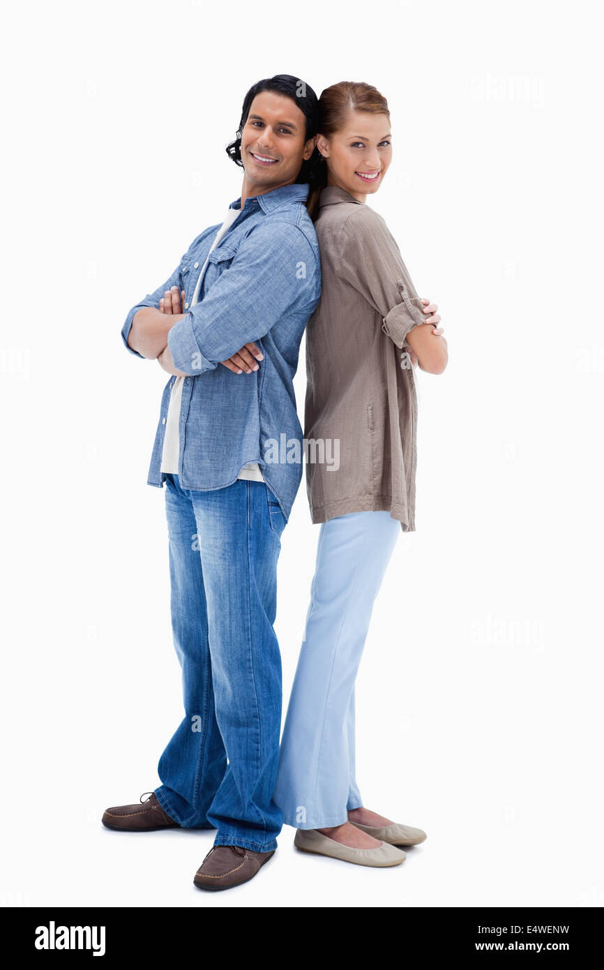 Smiling young couple standing back to back Stock Photo - Alamy