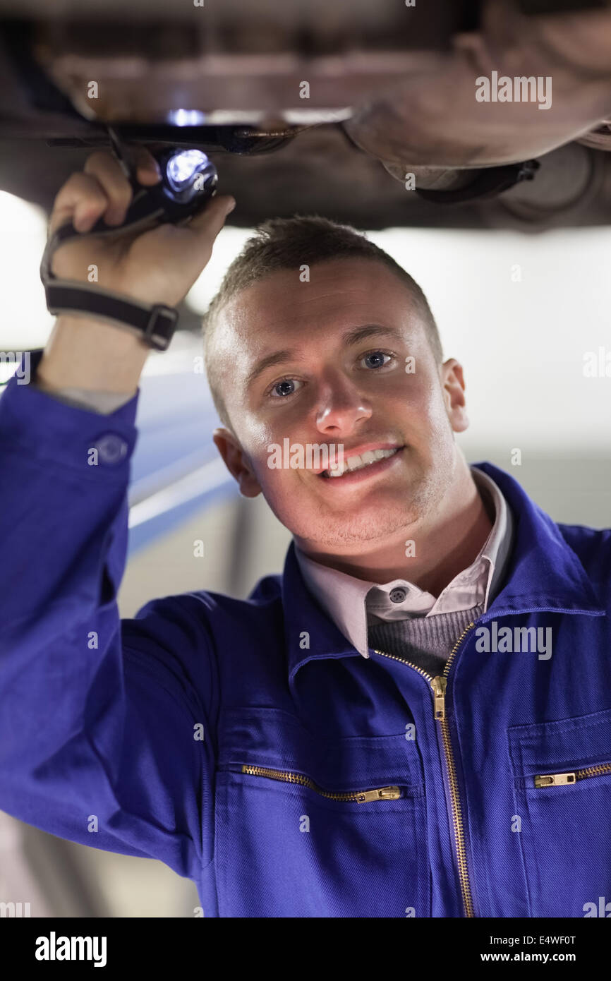 Mechanic illuminating the below of a car Stock Photo - Alamy