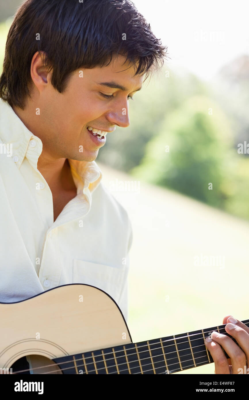 Man smiling as he plays a guitar Stock Photo - Alamy