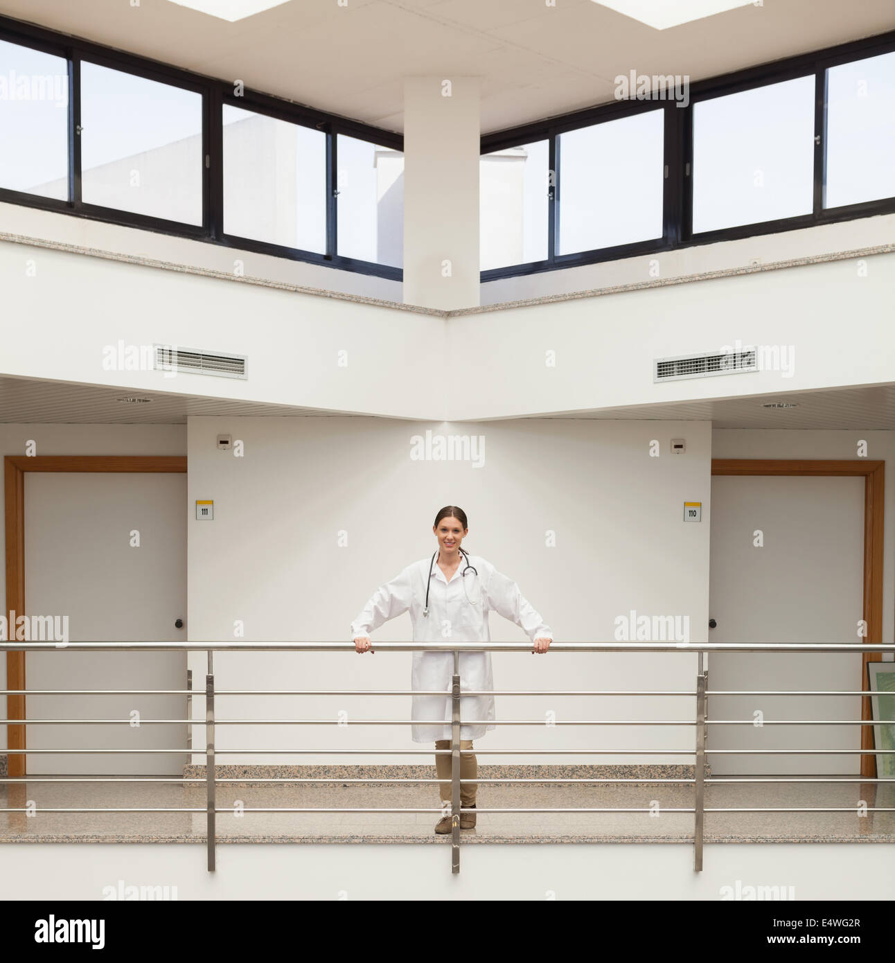 Smiling female doctor leaning on the railing Stock Photo - Alamy