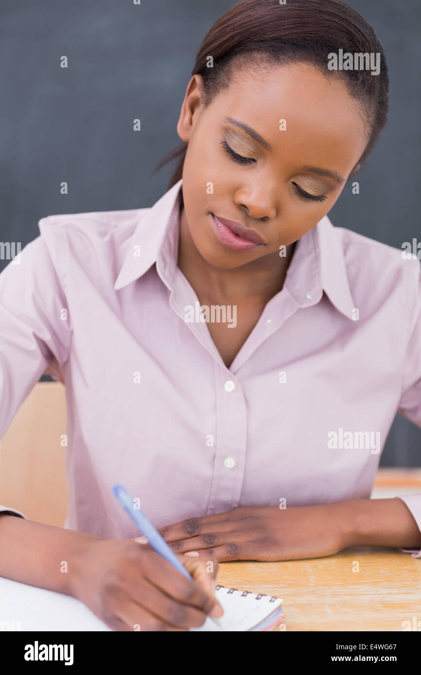 Black teacher writing on a notebook Stock Photo - Alamy