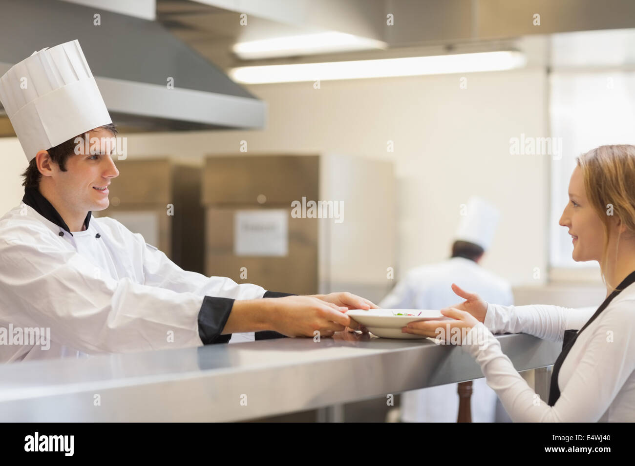 Chef giving a plate to the waitress Stock Photo - Alamy