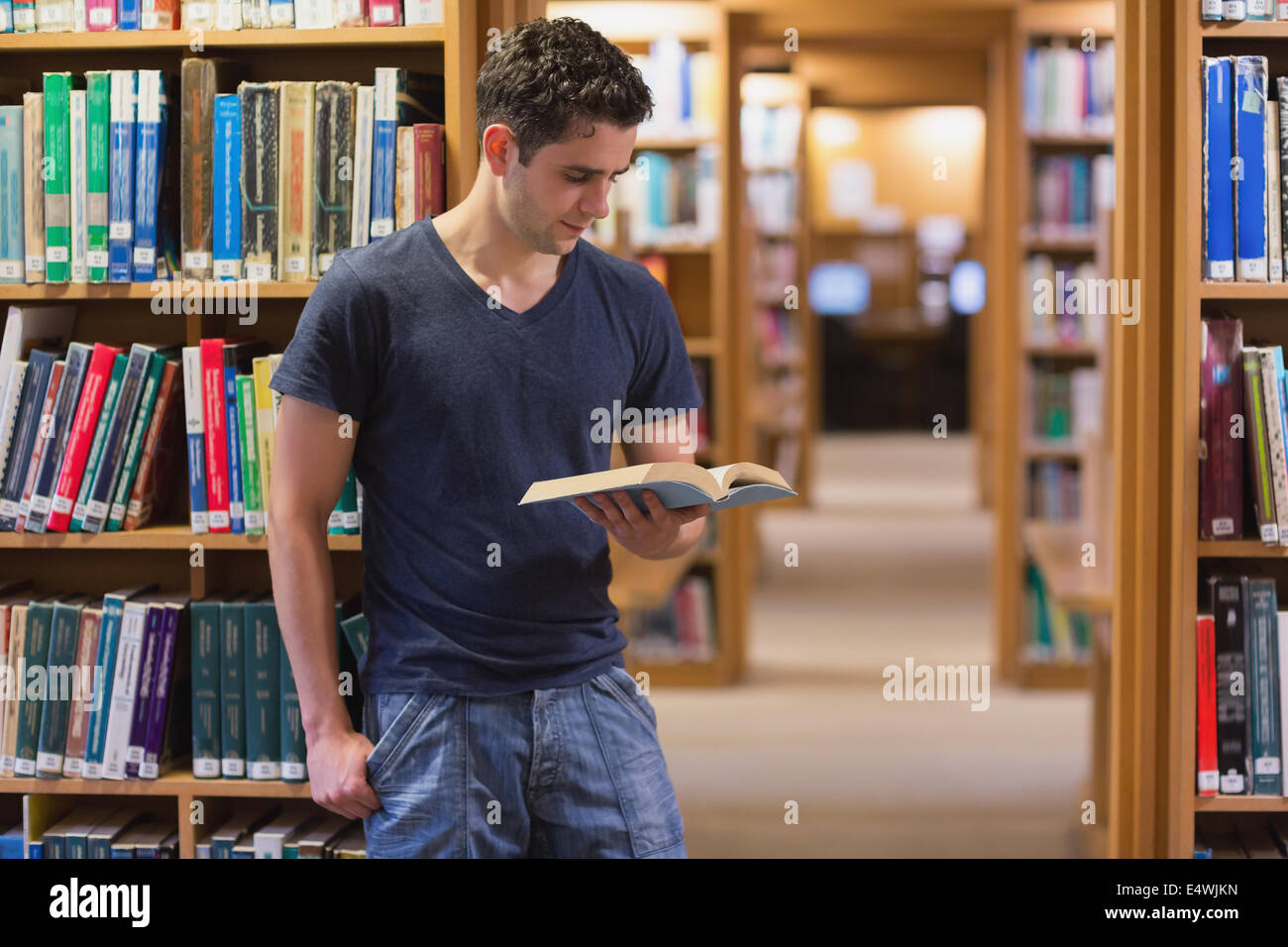 Man standing at the library holding a book Stock Photo - Alamy
