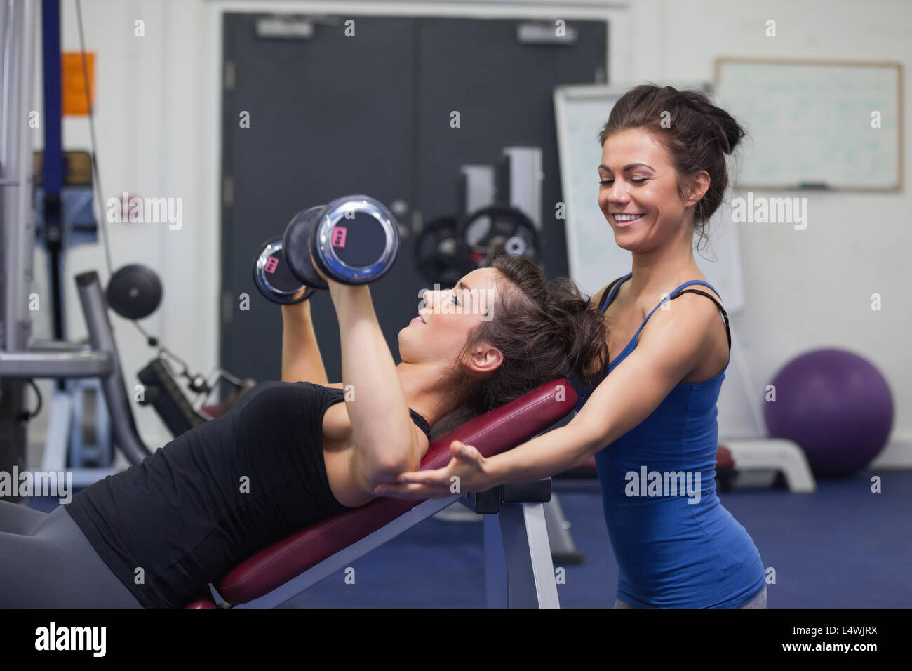 Female trainer teaching woman lifting weights Stock Photo - Alamy
