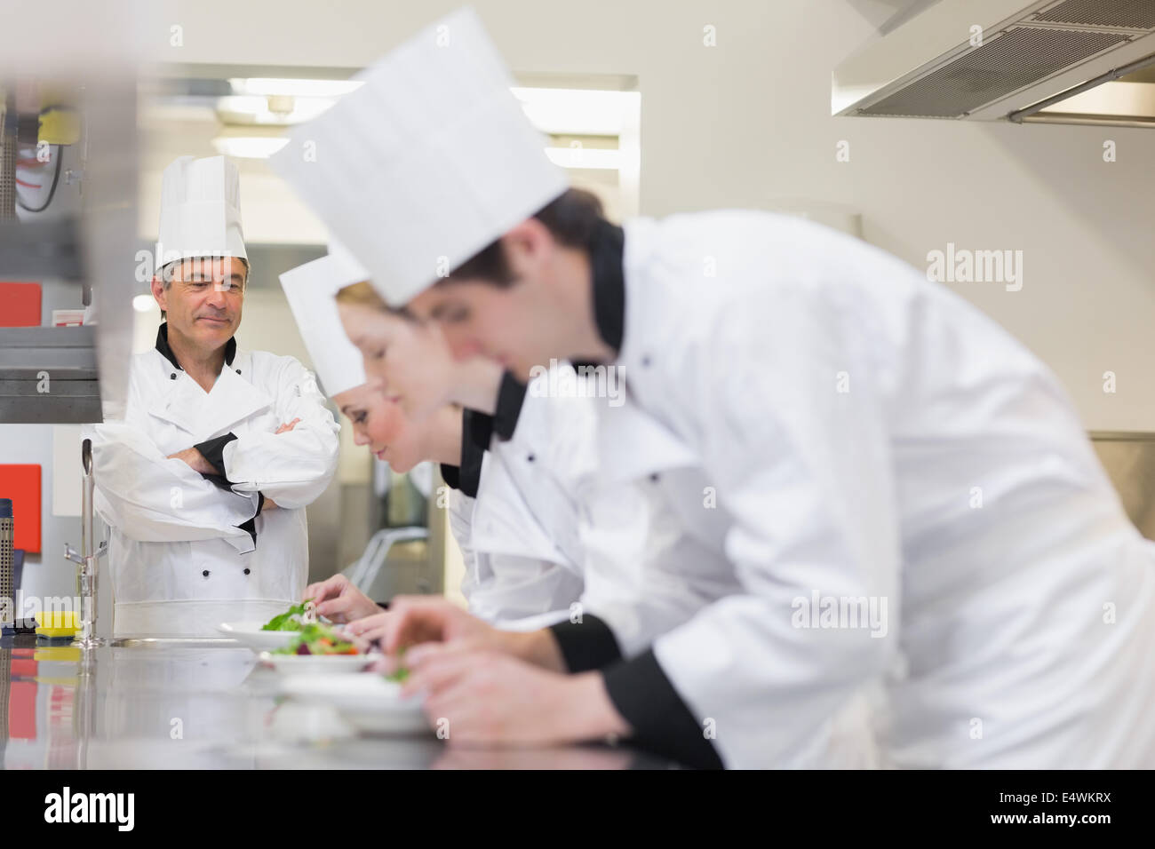 Chef supervising others making salads Stock Photo - Alamy